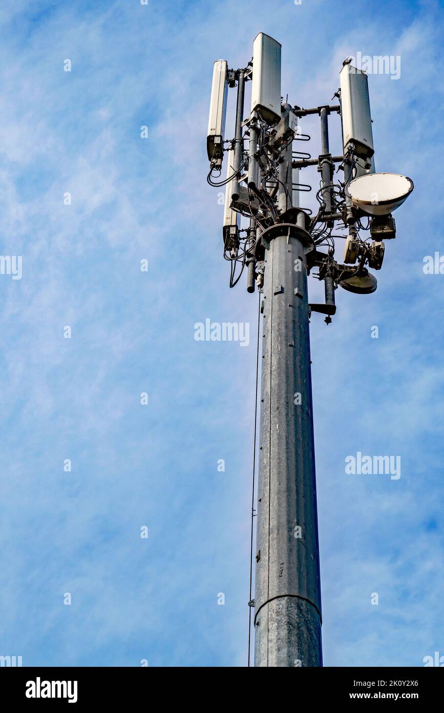 Telecoms mast with receiver/transmitter against blue sky with white ...
