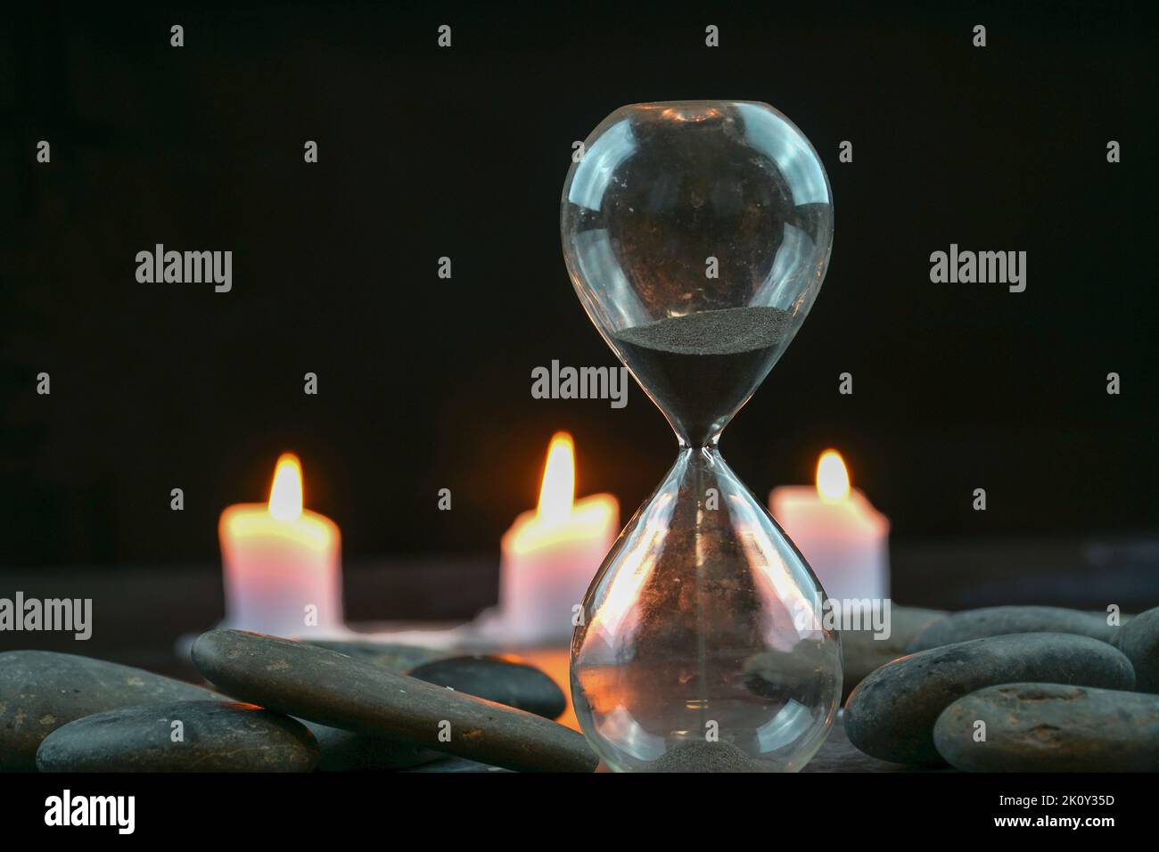 A close-up shot of an hourglass with the background of blurred burning ...