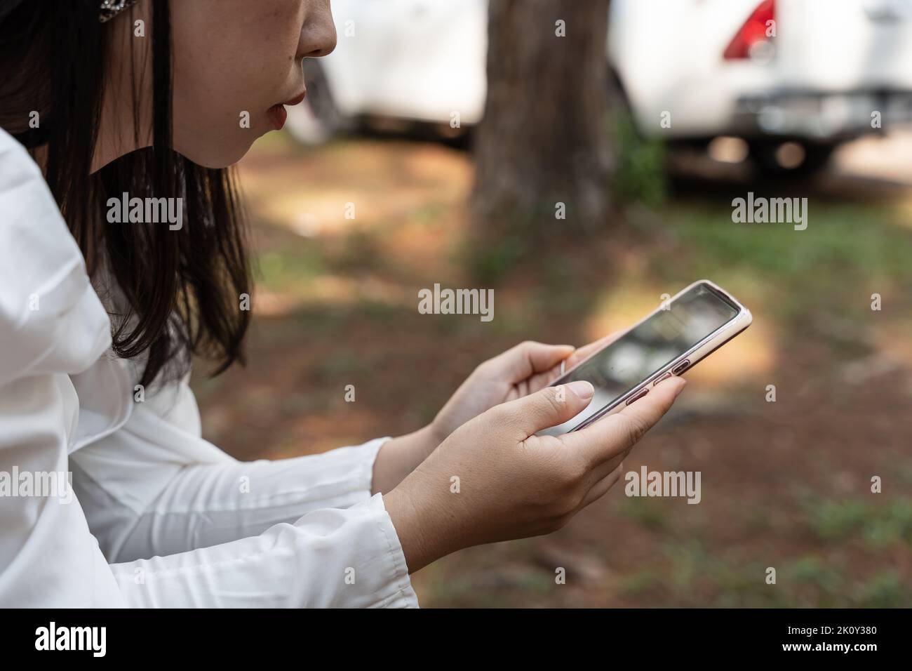 Close up of image woman hand using mobile phone in park. Searching or ...