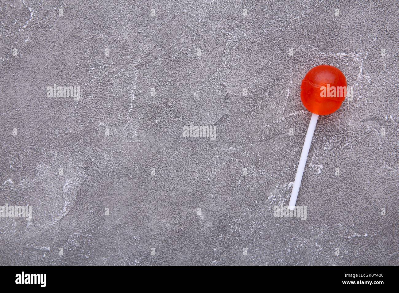 Red lollipop on grey concrete background. Studio shot Stock Photo - Alamy
