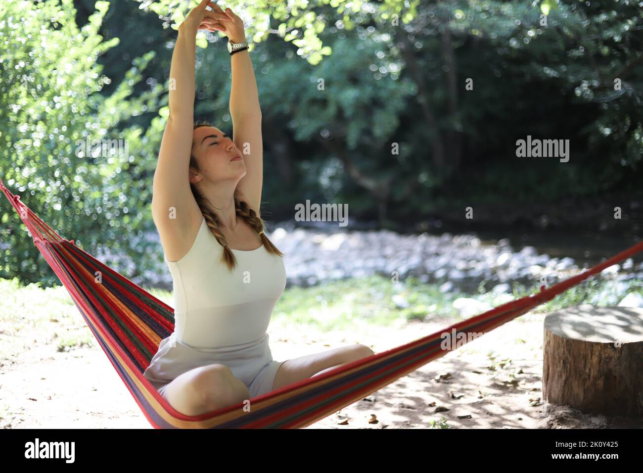 A shallow focus shot of a female sitting on the hammock and exercising ...