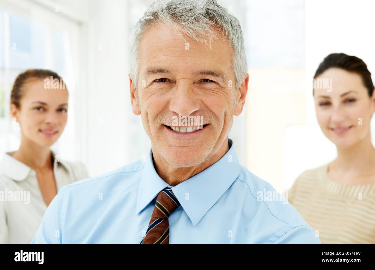 Smiling senior businessman with colleague in background. Happy senior ...