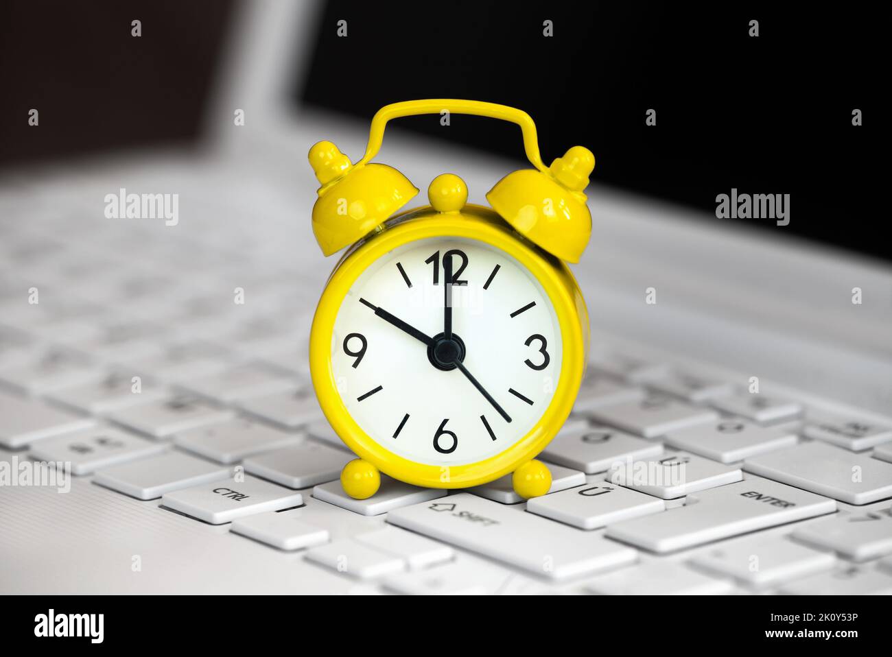 Yellow alarm clock on a white laptop, daylight savings time background ...