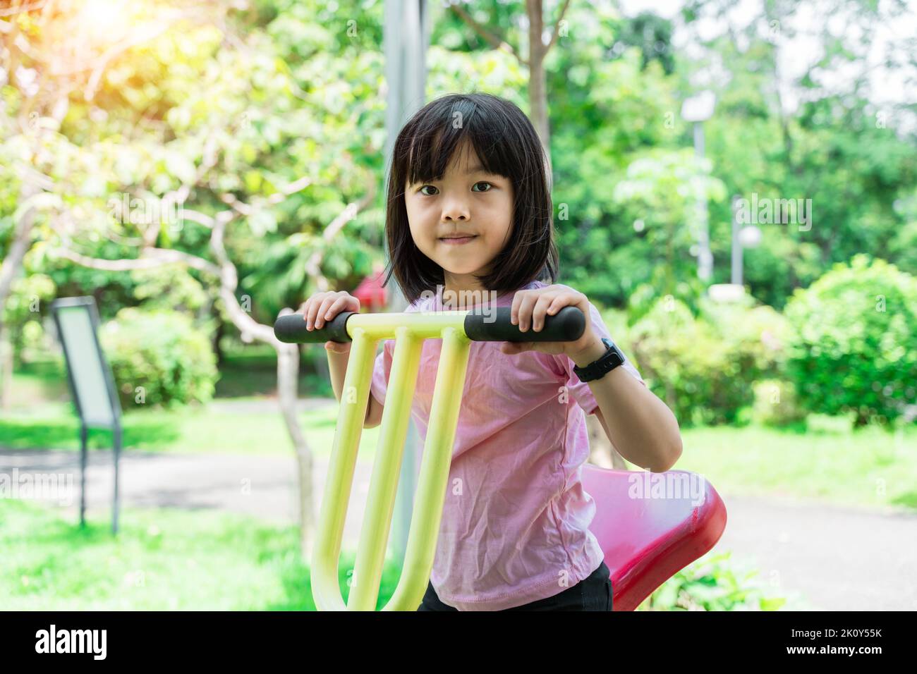 Cheerful child girl playing on playground in the park. Healthy summer ...