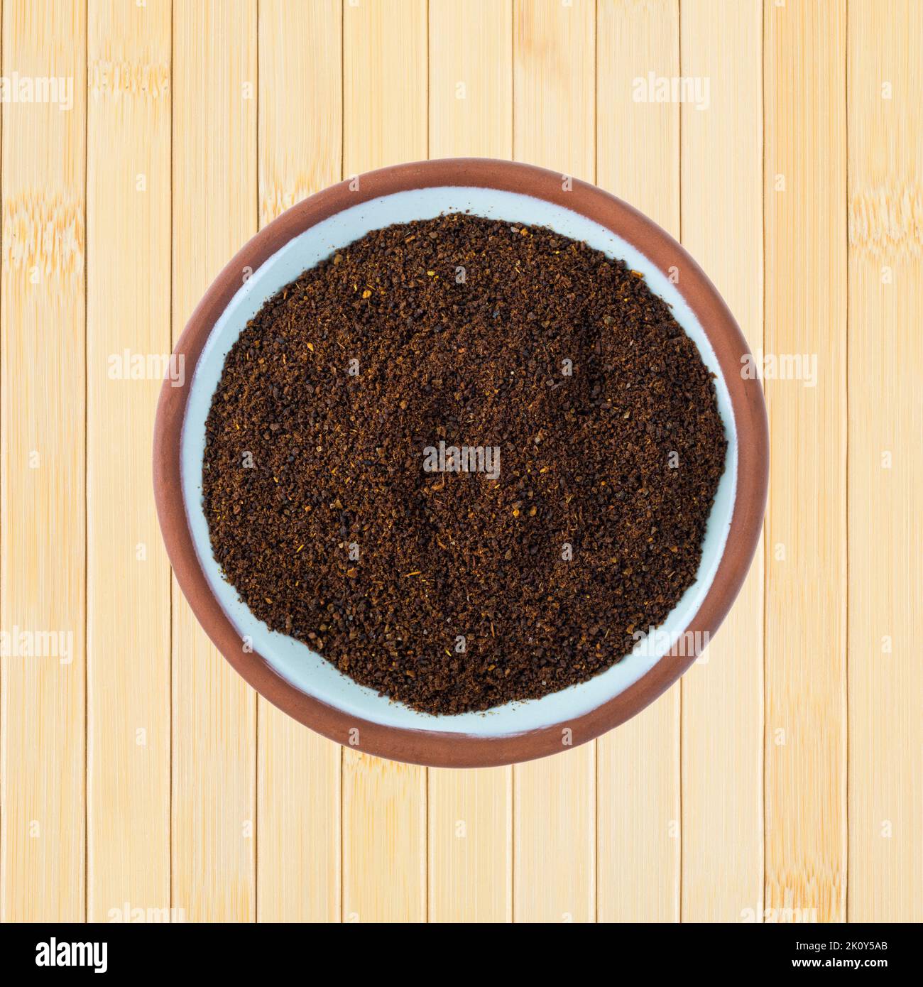 Chili powder in a small terracotta spice bowl on a wood background ...