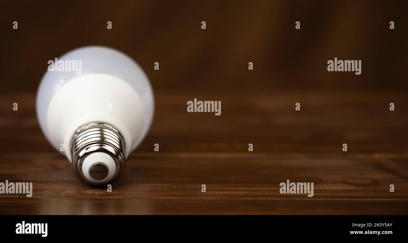 Light bulb on a brown wooden background. Saving energy, electricity ...