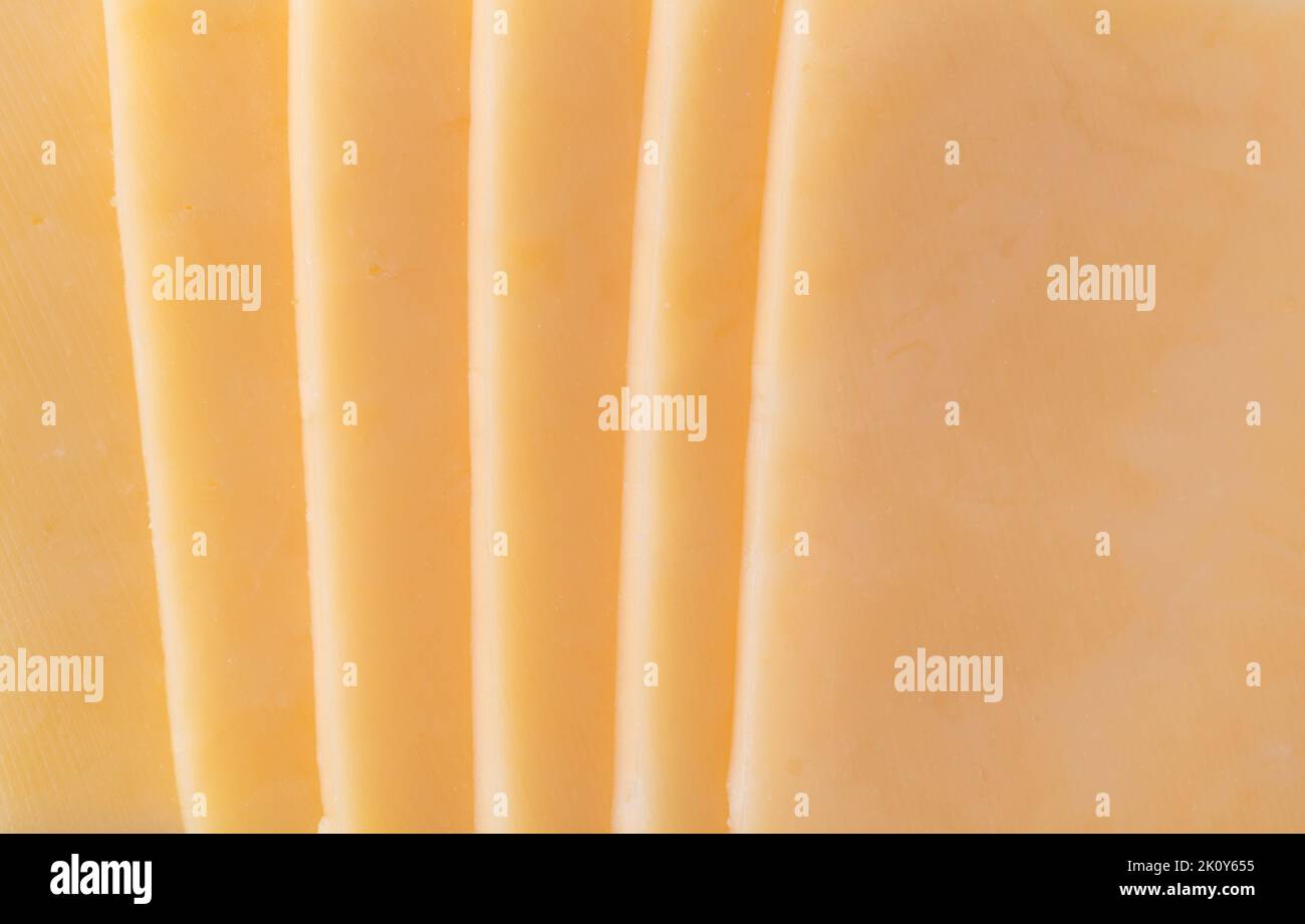 Very close view of several slices of gouda cheese illuminated with ...