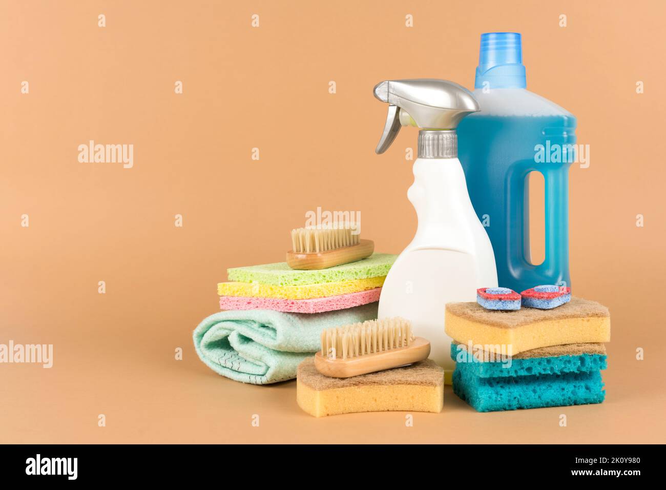 Different cleaning household supplies against light brown background ...