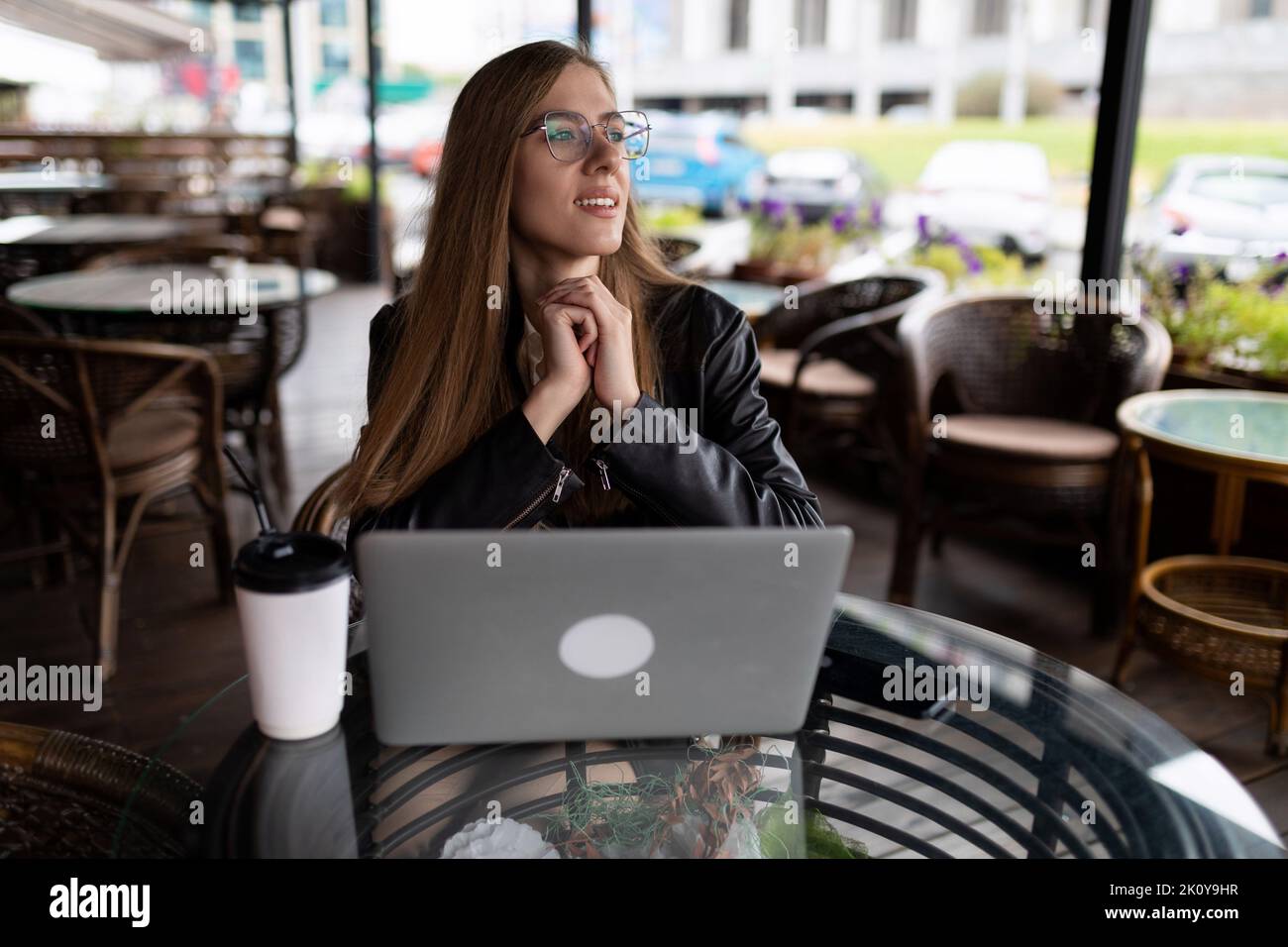 young female freelancer working on a laptop in a city cafe Stock Photo ...