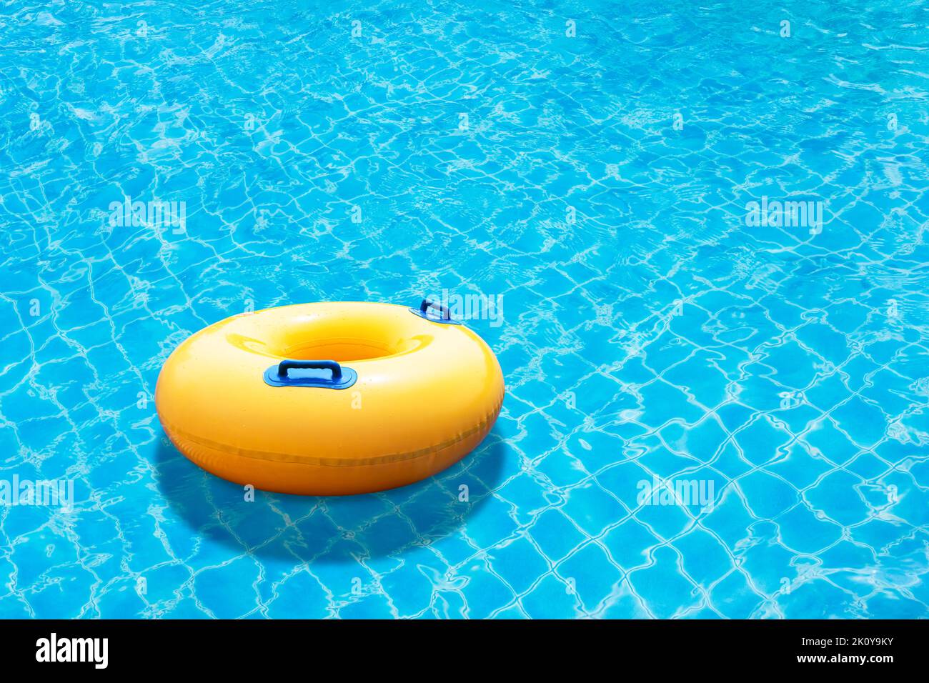 Yellow ring floating in a blue wave water on the outdoor swimming pool ...