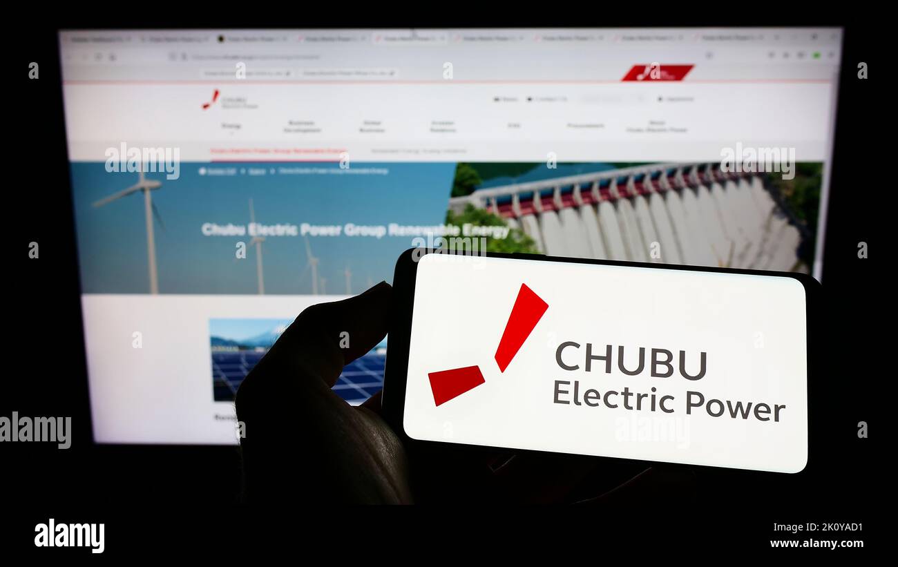 Person holding cellphone with logo of Japanese company Chubu Electric Power Co. Inc. on screen ...