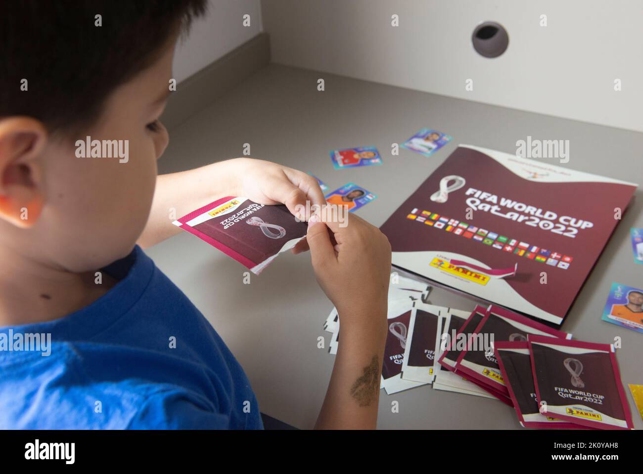 Bauru, Brazil - 12.09.22: Back view of boy opening sticker packs to ...
