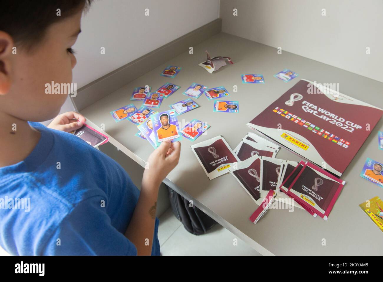 Bauru, Brazil - 12.09.22: Back view of boy opening sticker packs to ...