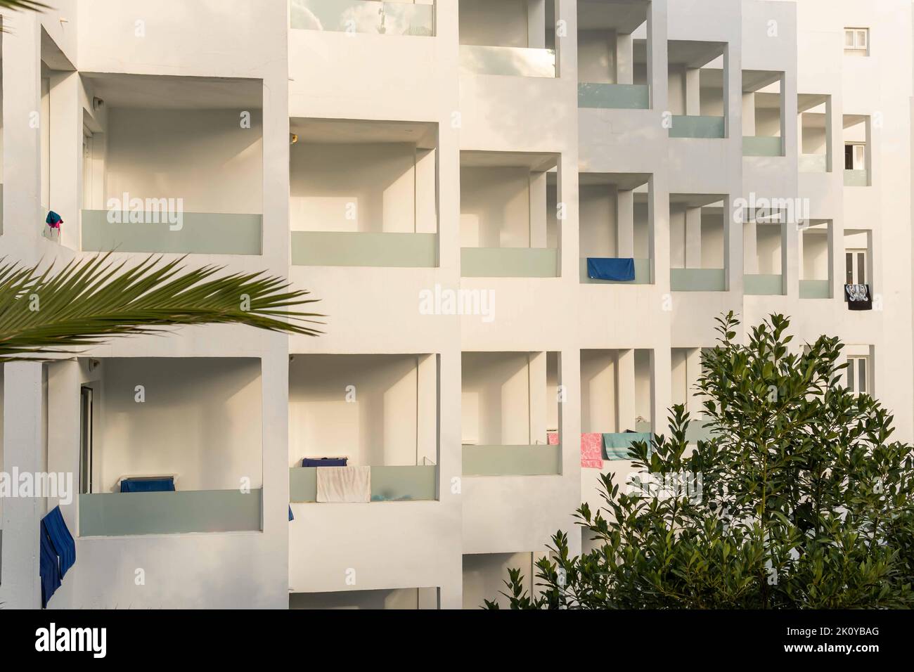 Facade with balconies of a white tourist hotel, with towels hanging ...