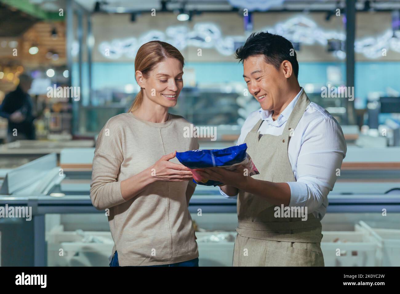 a male consultant in a grocery store advises a woman talking to ...