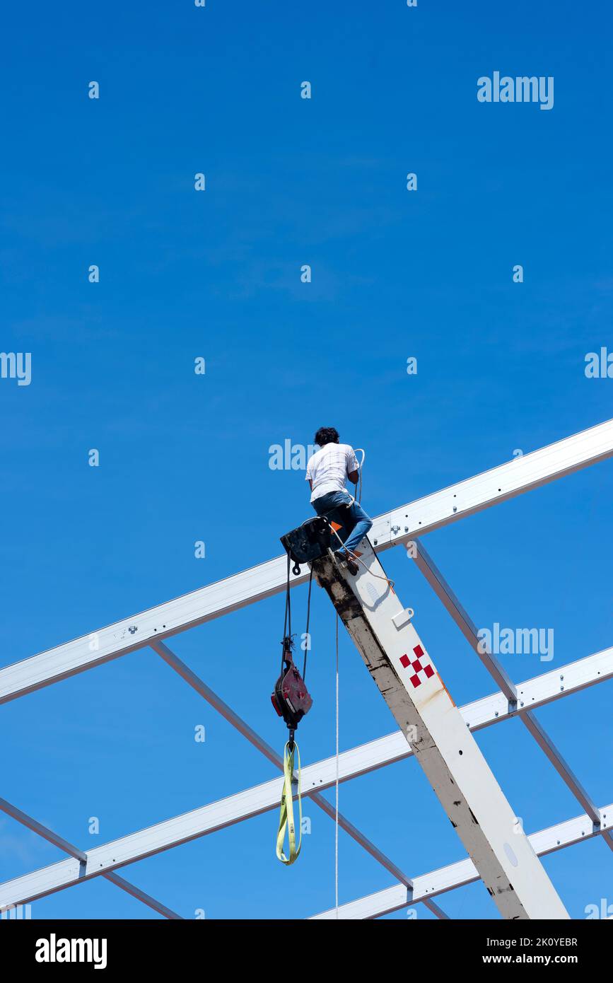A construction worker, balancing on the extended boom of a crane ...