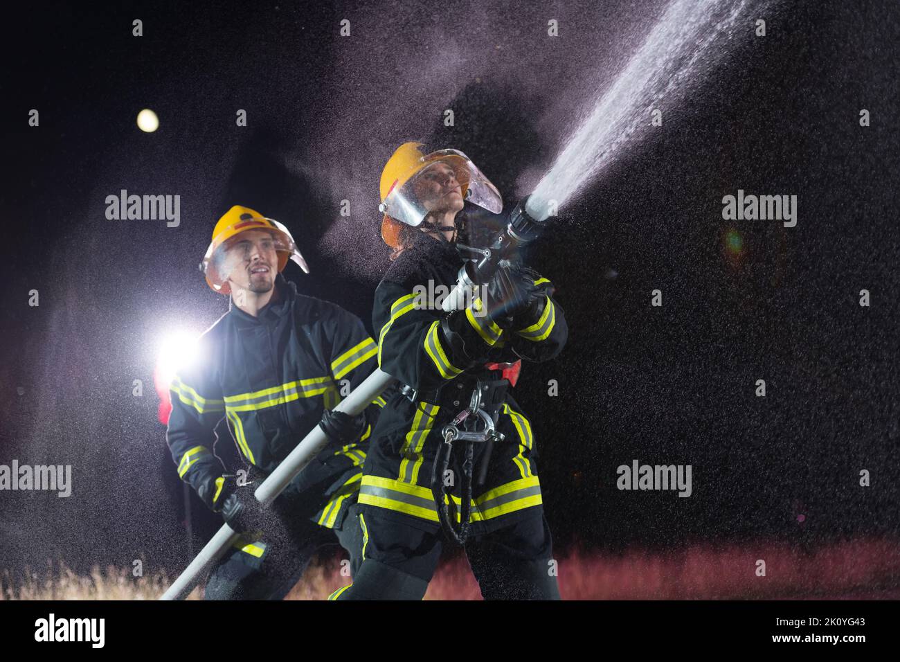 Firefighters using a water hose to eliminate a fire hazard. Team of ...