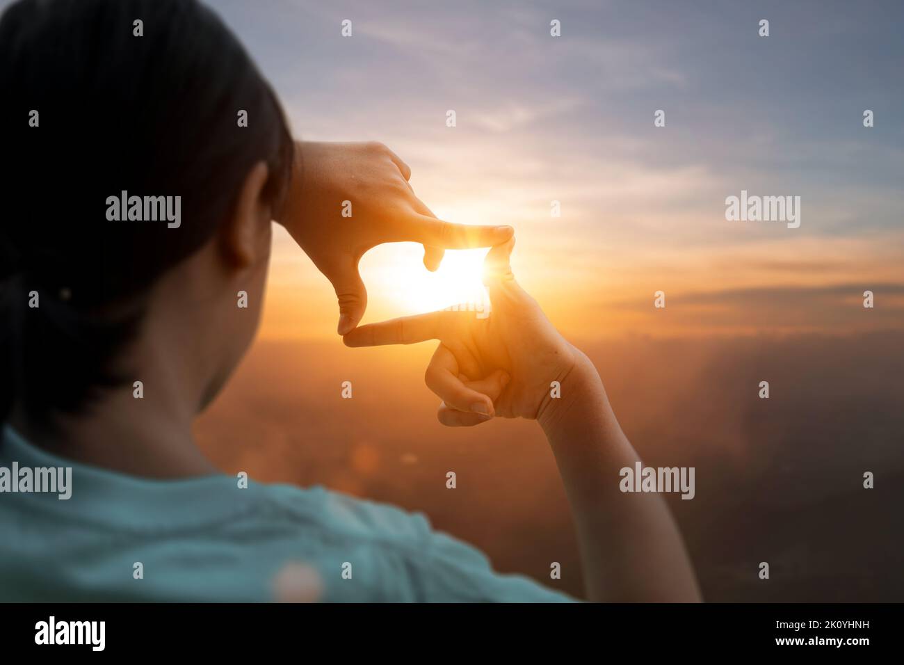 Child girl making frame around the sun with her hands capturing in the ...