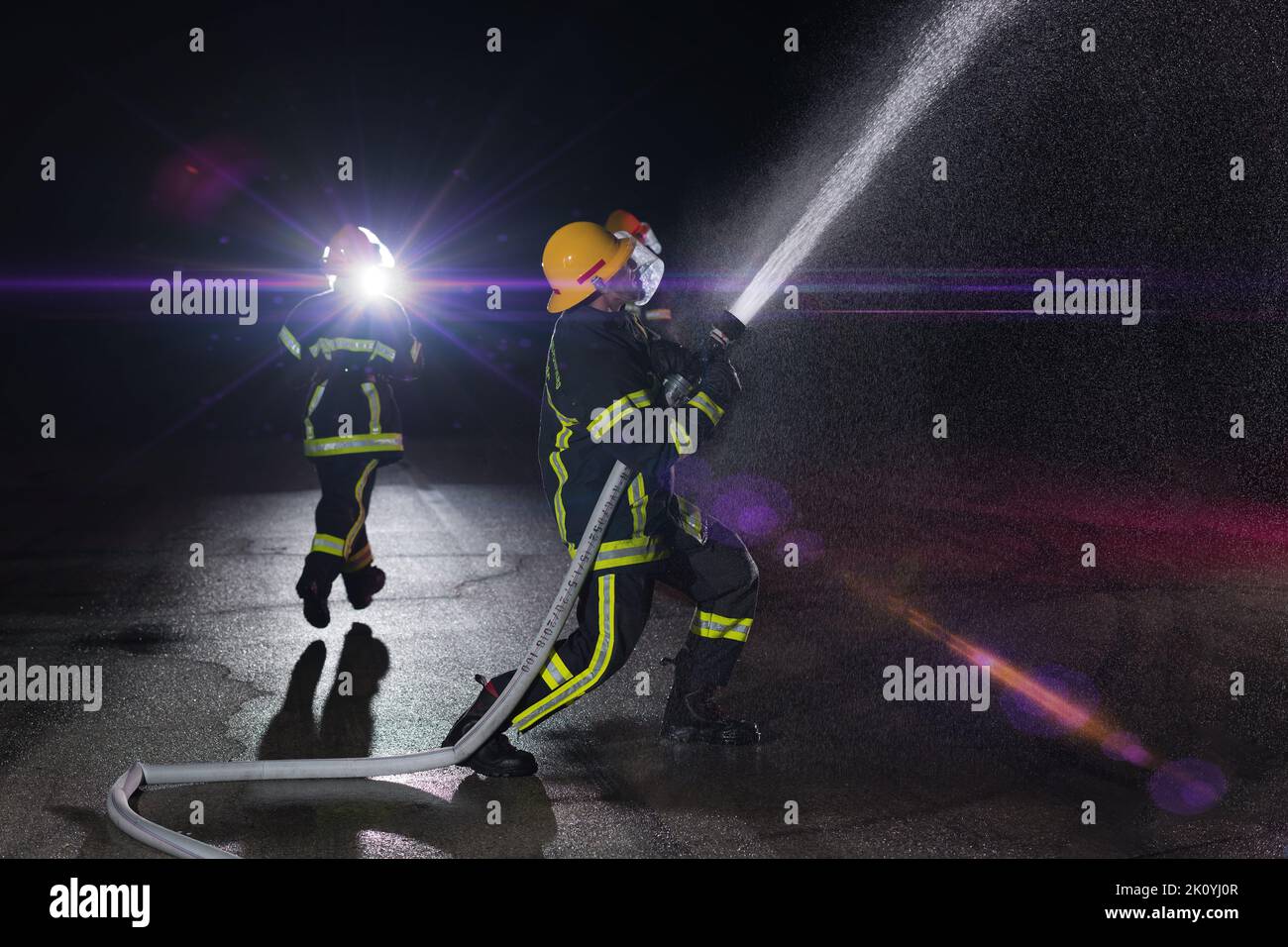 Firefighters use a water hose to eliminate a fire hazard. Team of ...