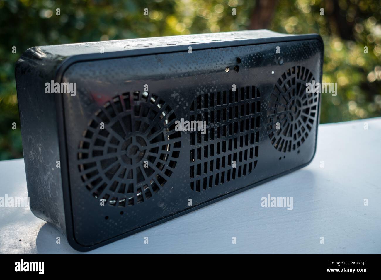 A close up shot of an old black blue tooth speaker outdoors in natural ...
