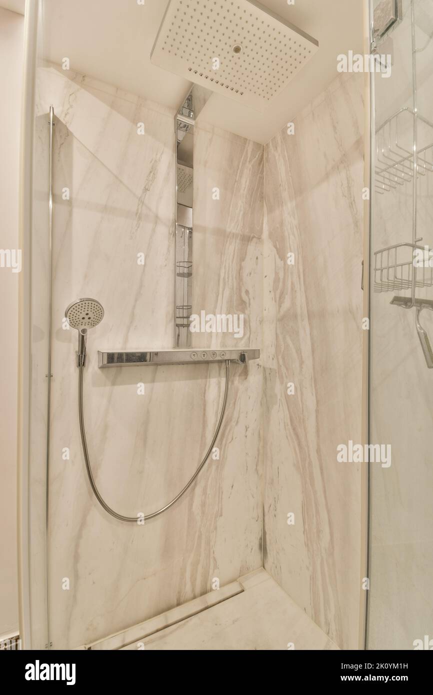 Shower faucets attached to tiled wall near glass partition and cink in ...