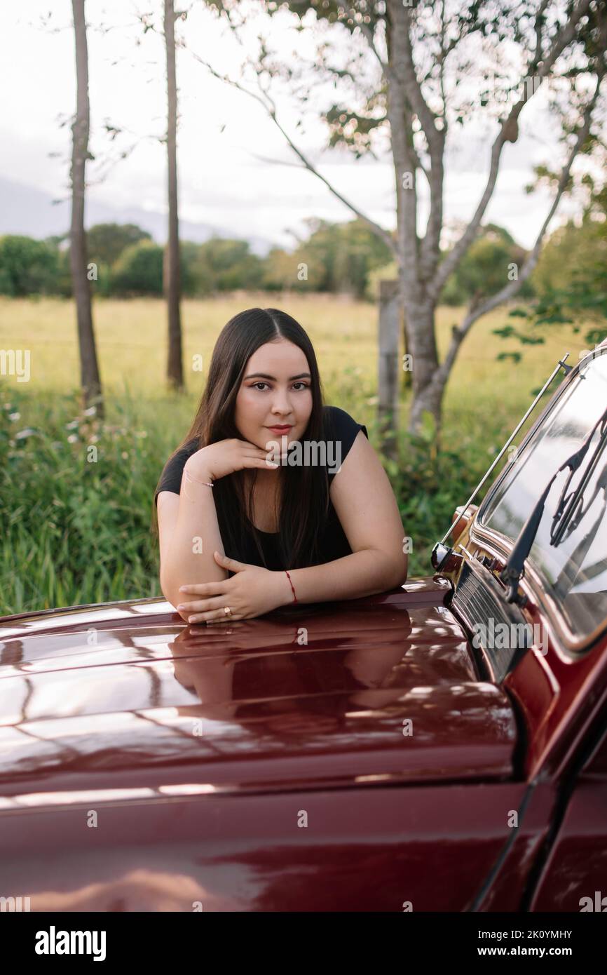 Relaxed girl on a car in the middle of nature and a beautiful landscape ...