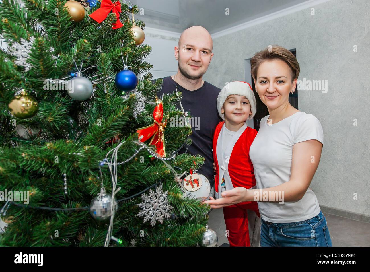 Family mom, dad and son in Santa costume posing near the Christmas tree ...