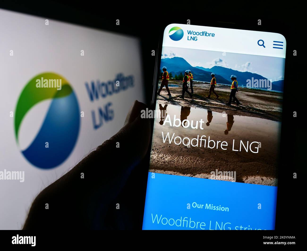 Person holding cellphone with webpage of Canadian gas company Woodfibre ...