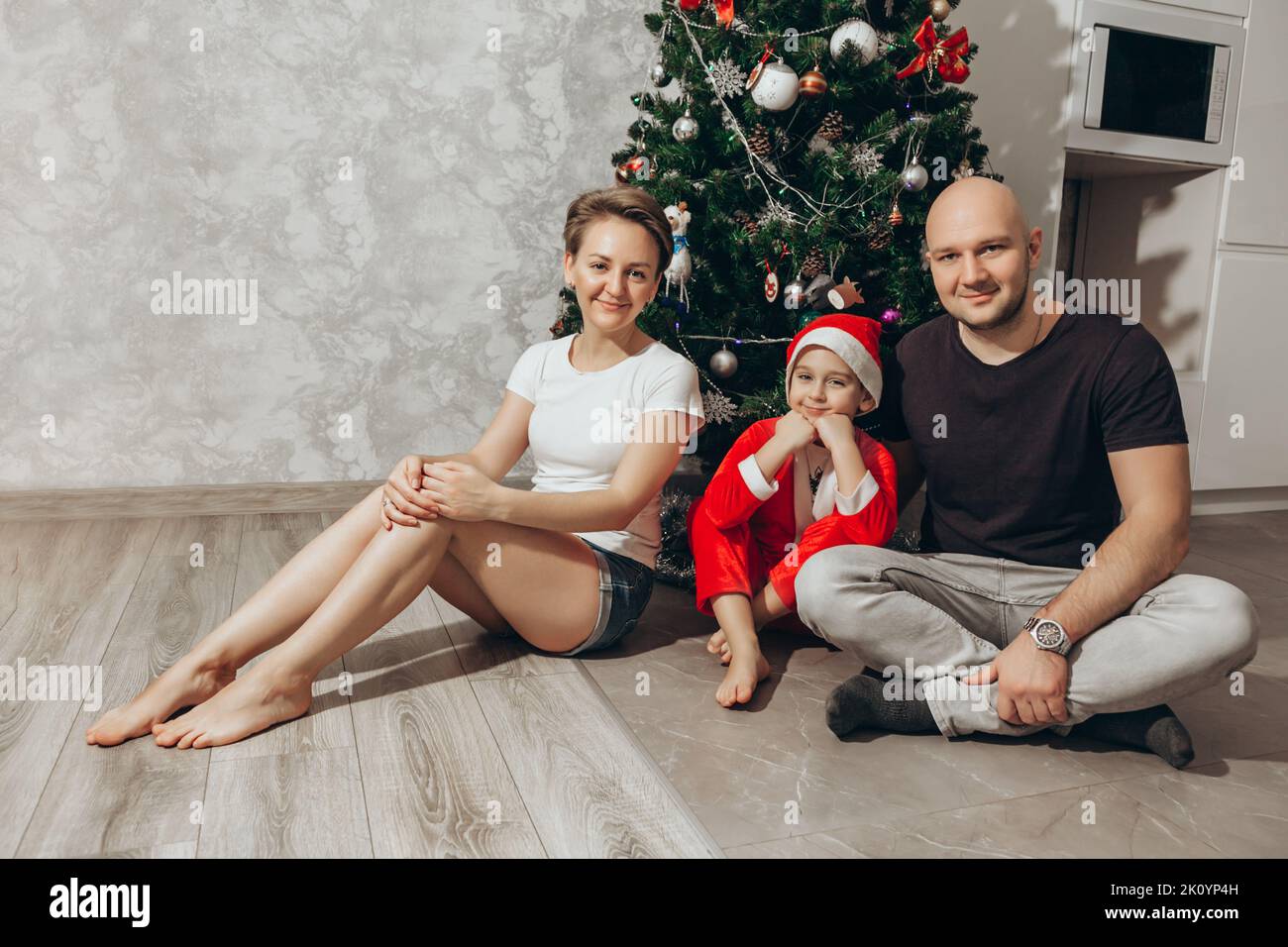 Family - mom, dad and son in Santa costume sitting under the Christmas ...