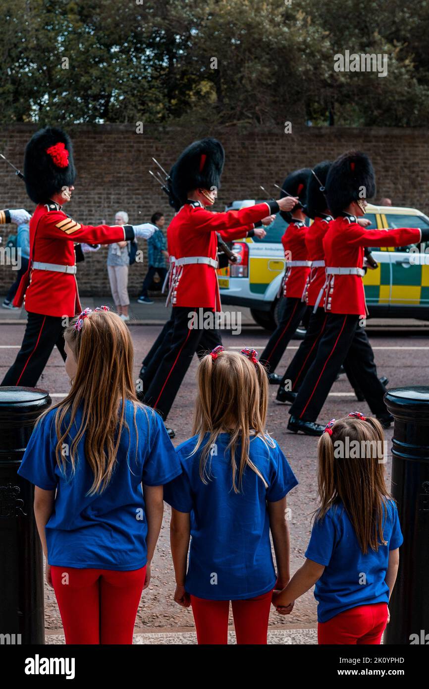 Three girls watch Royal guards march as part of ceremonies after the ...