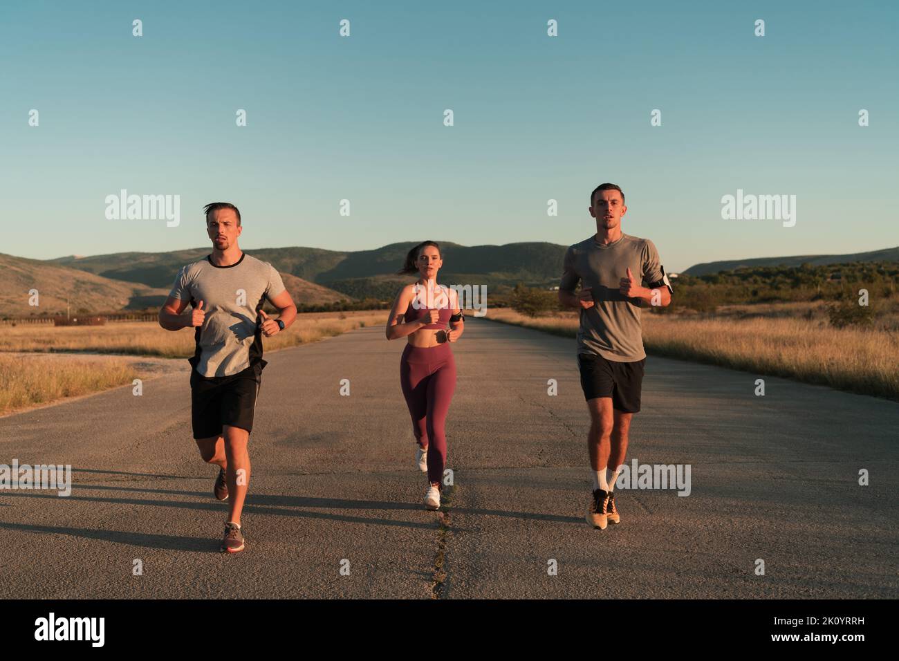 Three runners sprinting outdoors - Sportive people training in a urban ...
