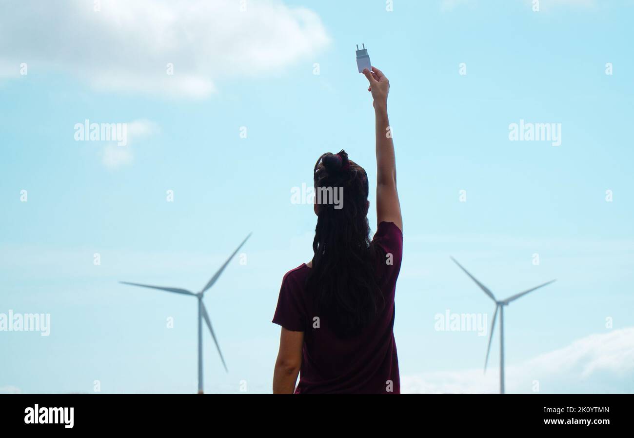 Renewable energy. Woman with a plug in a wind power plant Stock Photo ...