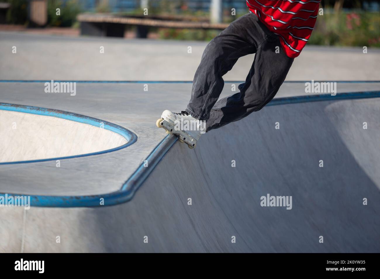 Inline skater doing trick in outdoor skatepark. In-line roller blader ...