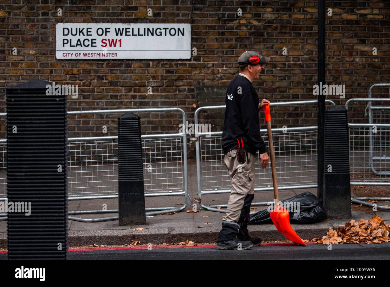 A worker sweeps dead leaves from Constitution Hill in preparation for ...