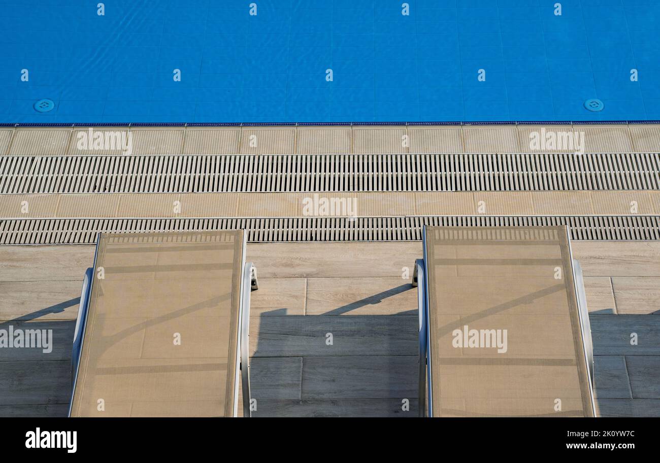 top view closeup of row of sunlounger chairs near a outdoor swimming ...