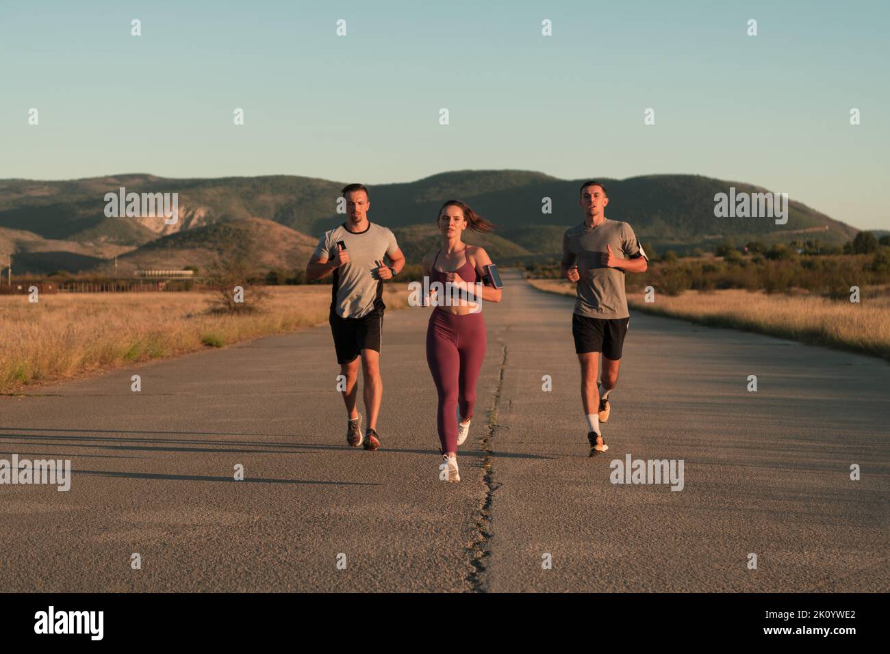 Three runners sprinting outdoors - Sportive people training in a urban ...