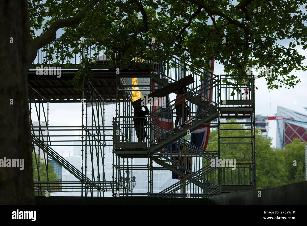 Temporary structures and workers are silhouetted against the Victoria ...