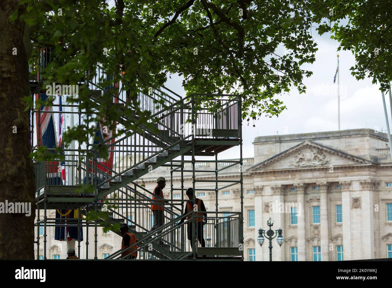 Temporary structures and workers are silhouetted against Buckingham ...