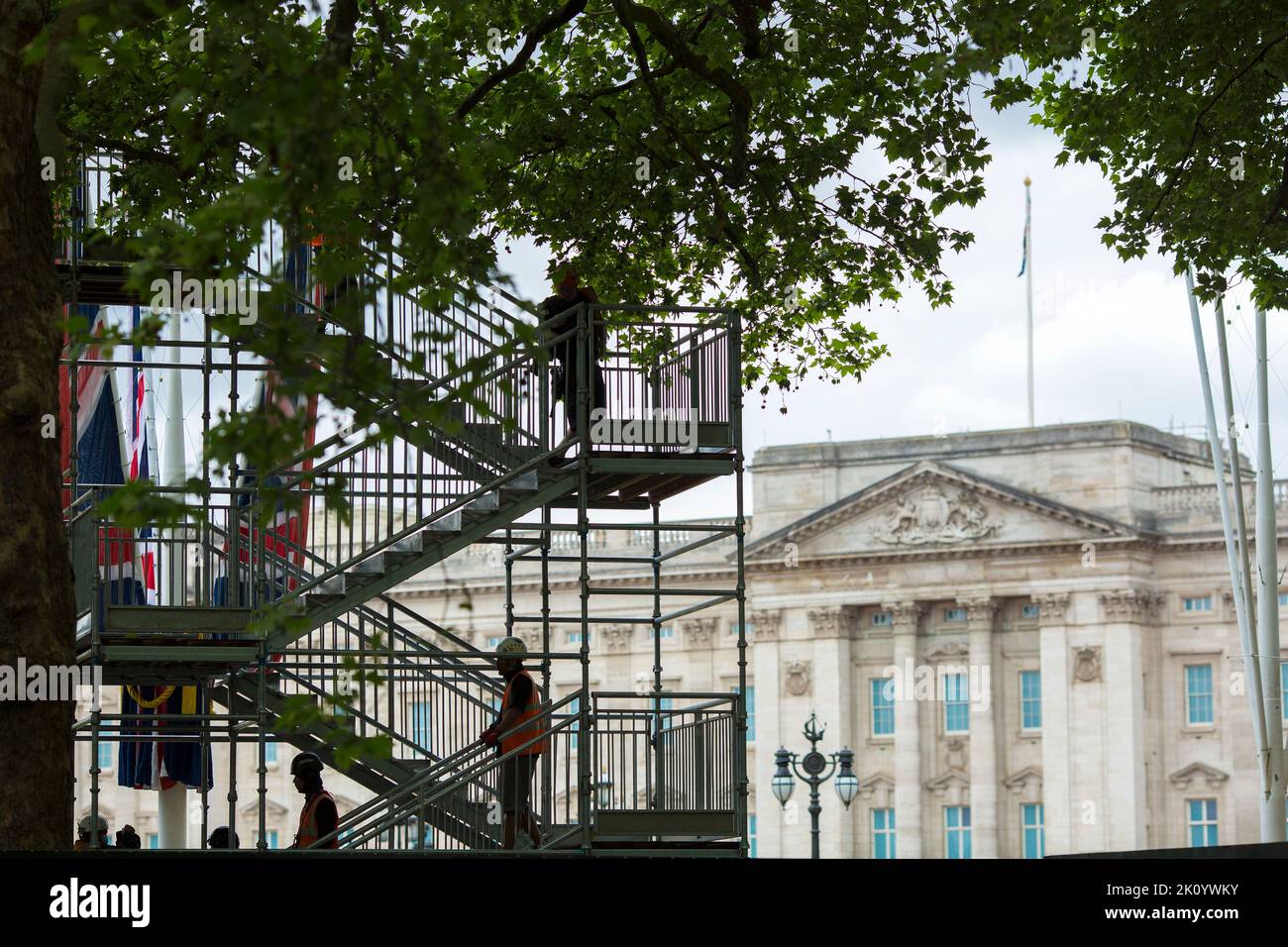 Temporary structures and workers are silhouetted against Buckingham ...