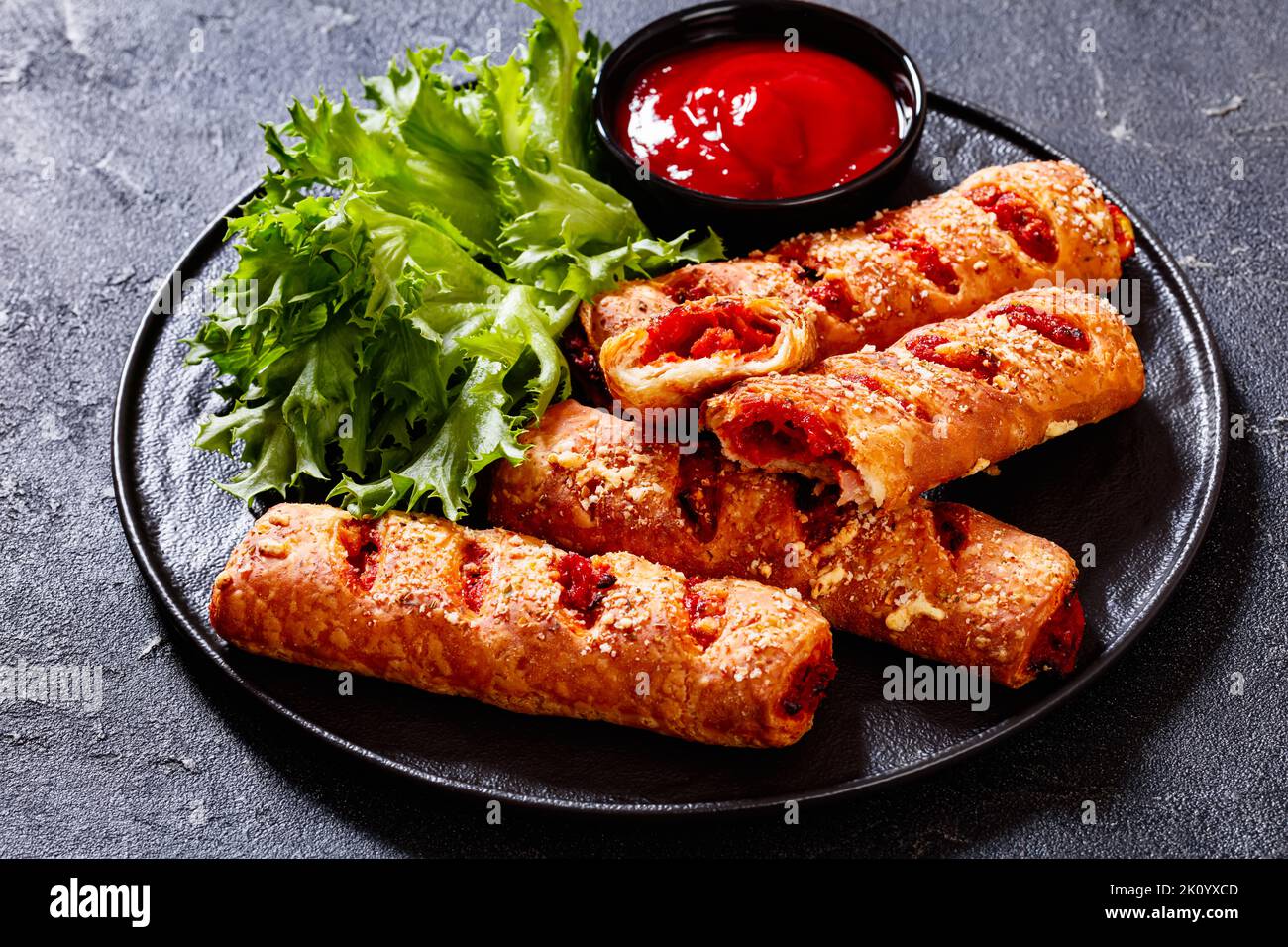 chorizo and semi-dried tomato puff pastry rolls on black plate with ...