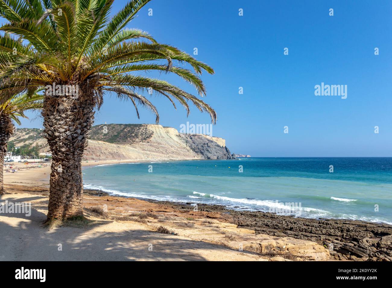 Coastal promenade at Luz beach, Lagos, Portugal. Palm trees and clear ...