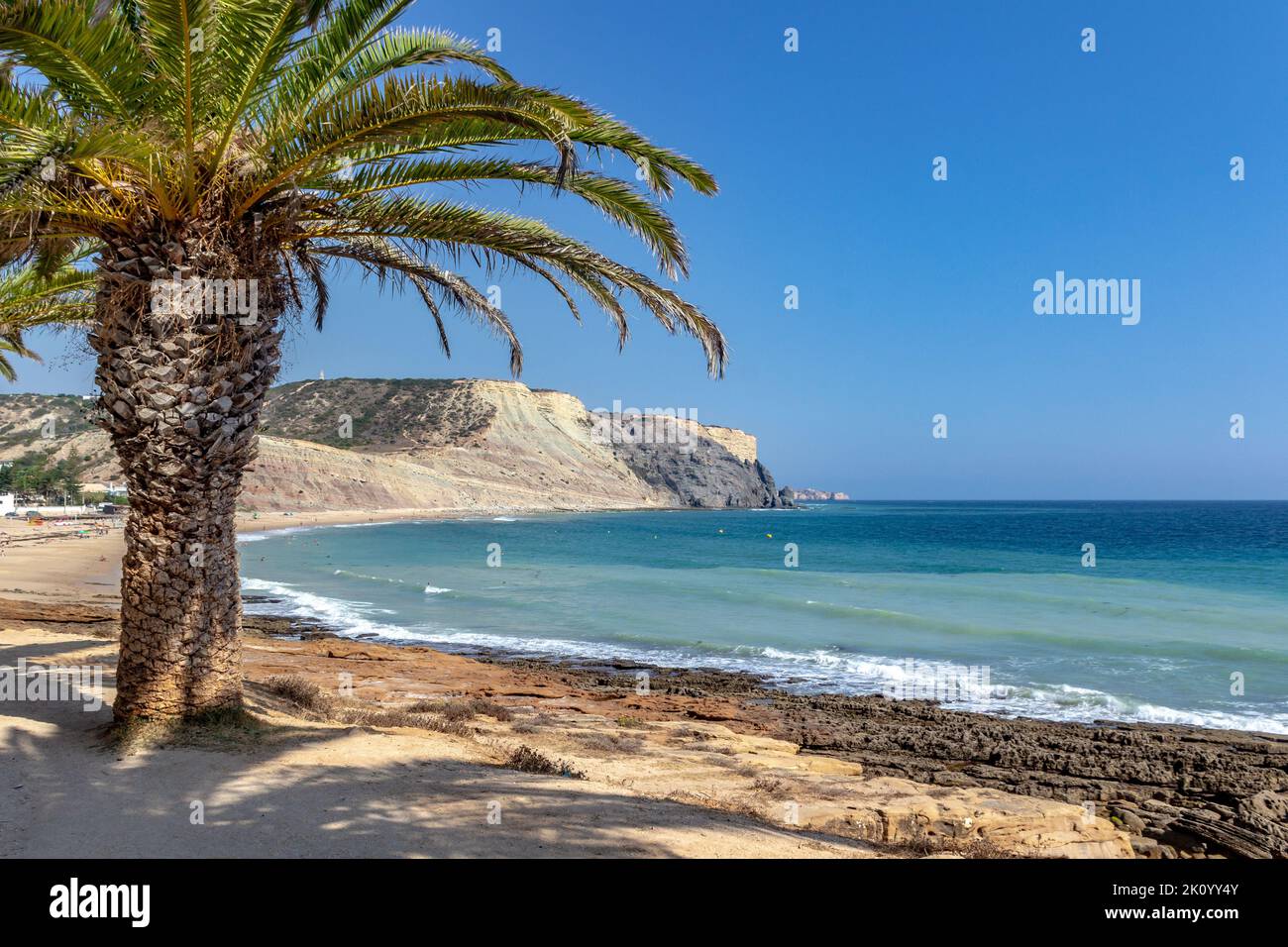 Coastal promenade at Luz beach, Lagos, Portugal. Palm trees and clear ...