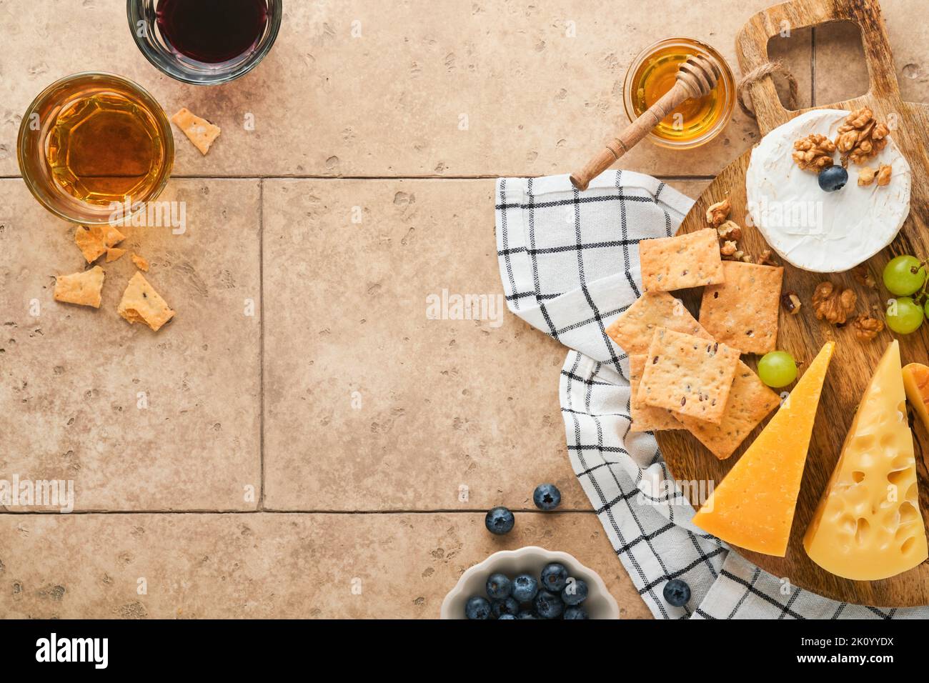 Assortment of cheese, honey, cracker, blueberries, grapes with red and ...