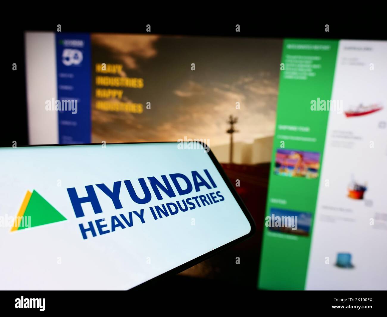 Mobile phone with logo of company Hyundai Heavy Industries Co. Ltd. (HHI) on screen in front of ...