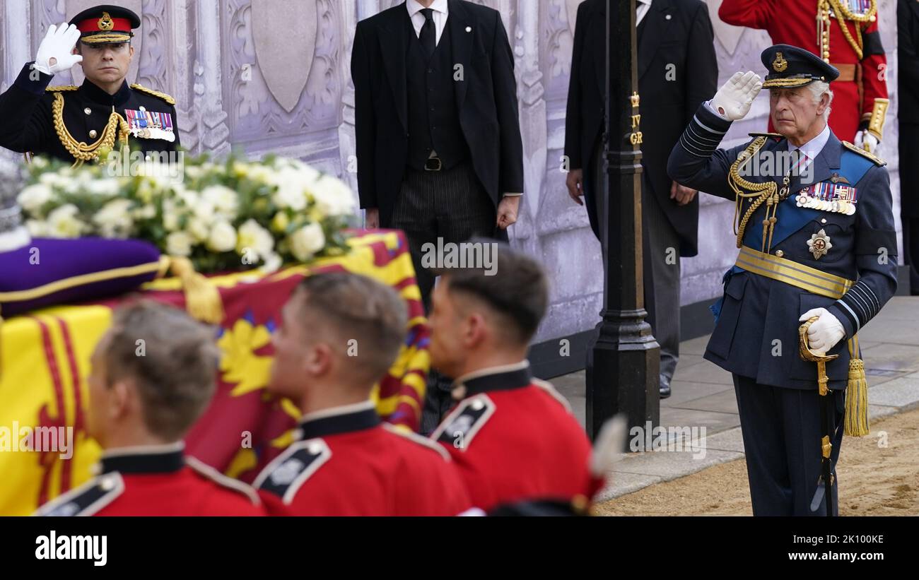 King Charles III, salutes as the bearer party carry the coffin of his ...