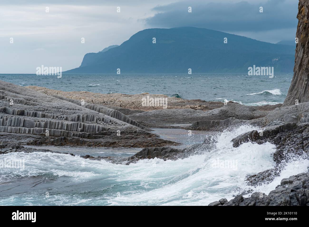 severe rocky seashore composed of columnar basalt against the backdrop ...