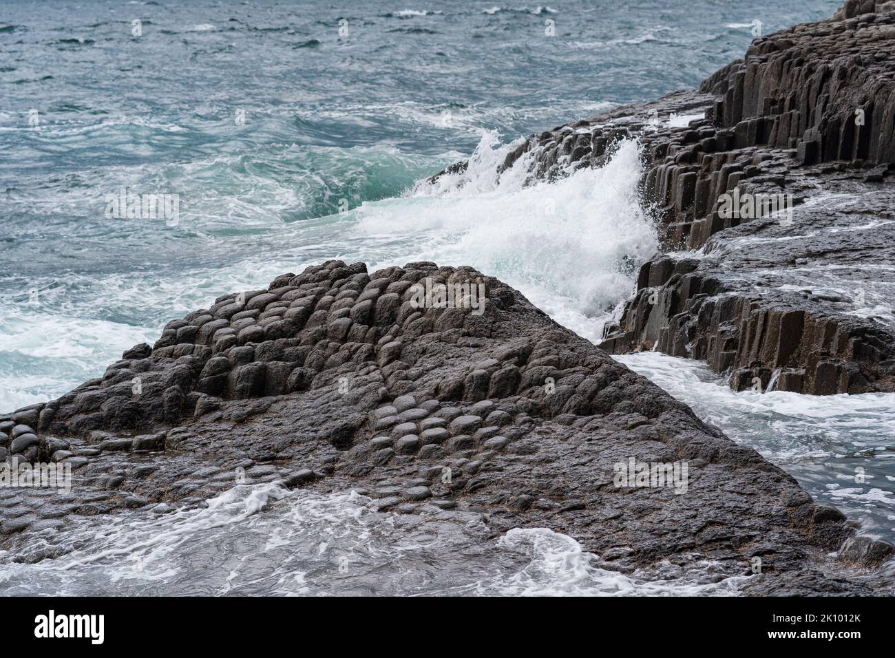 severe rocky seashore composed of columnar basalt against the stormy ...