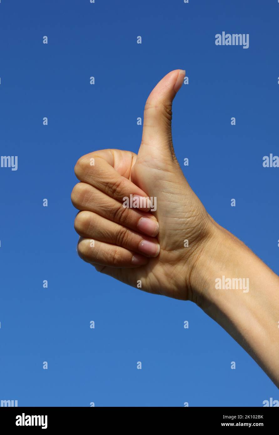 hand with the thumb up to indicate that everything is fine and blue sky ...