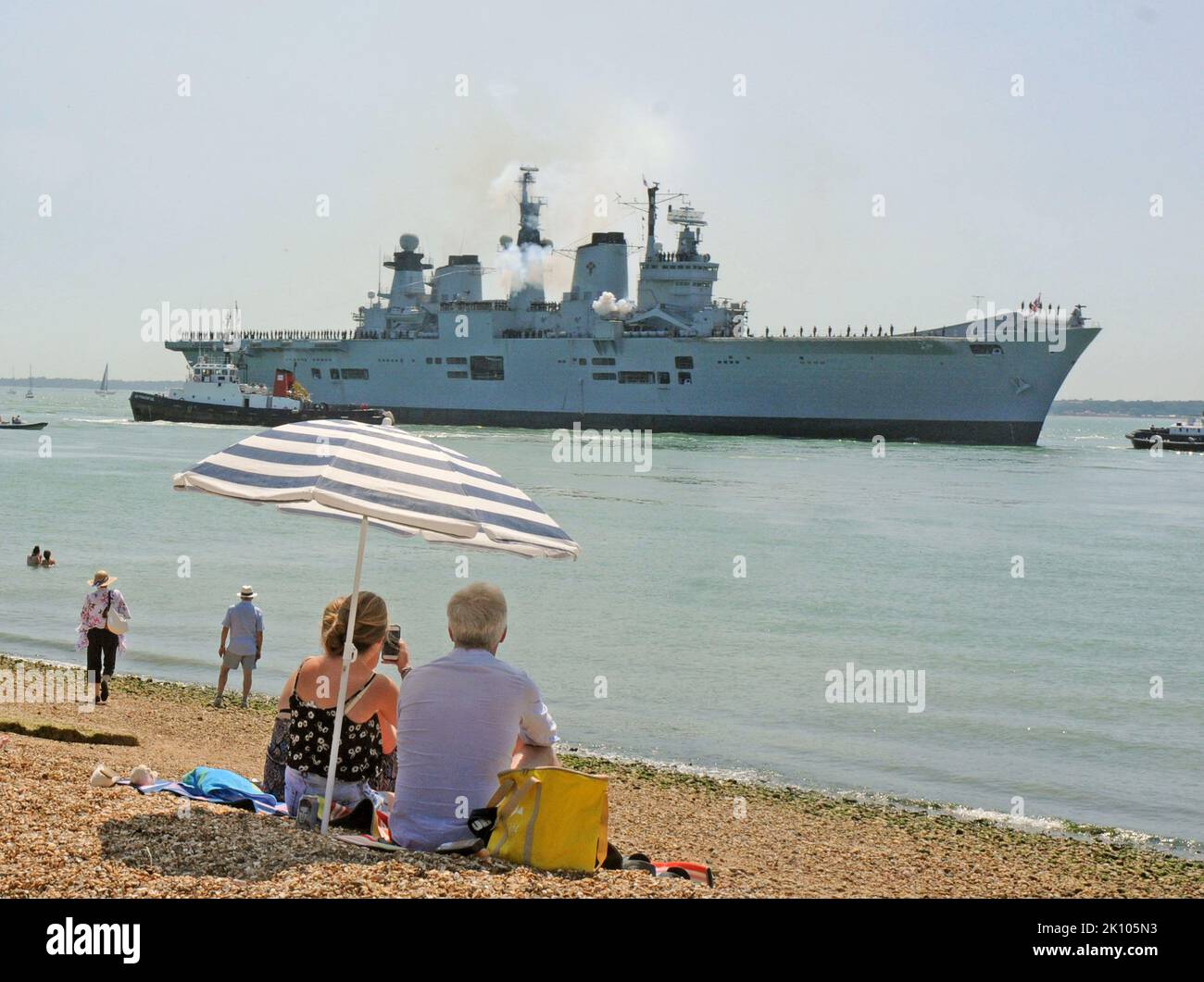 HMS ILLUSTRIOUS FIRES A SALUTE AS SHE PASSES SUNBATHERS ON SOUTHSEA ...