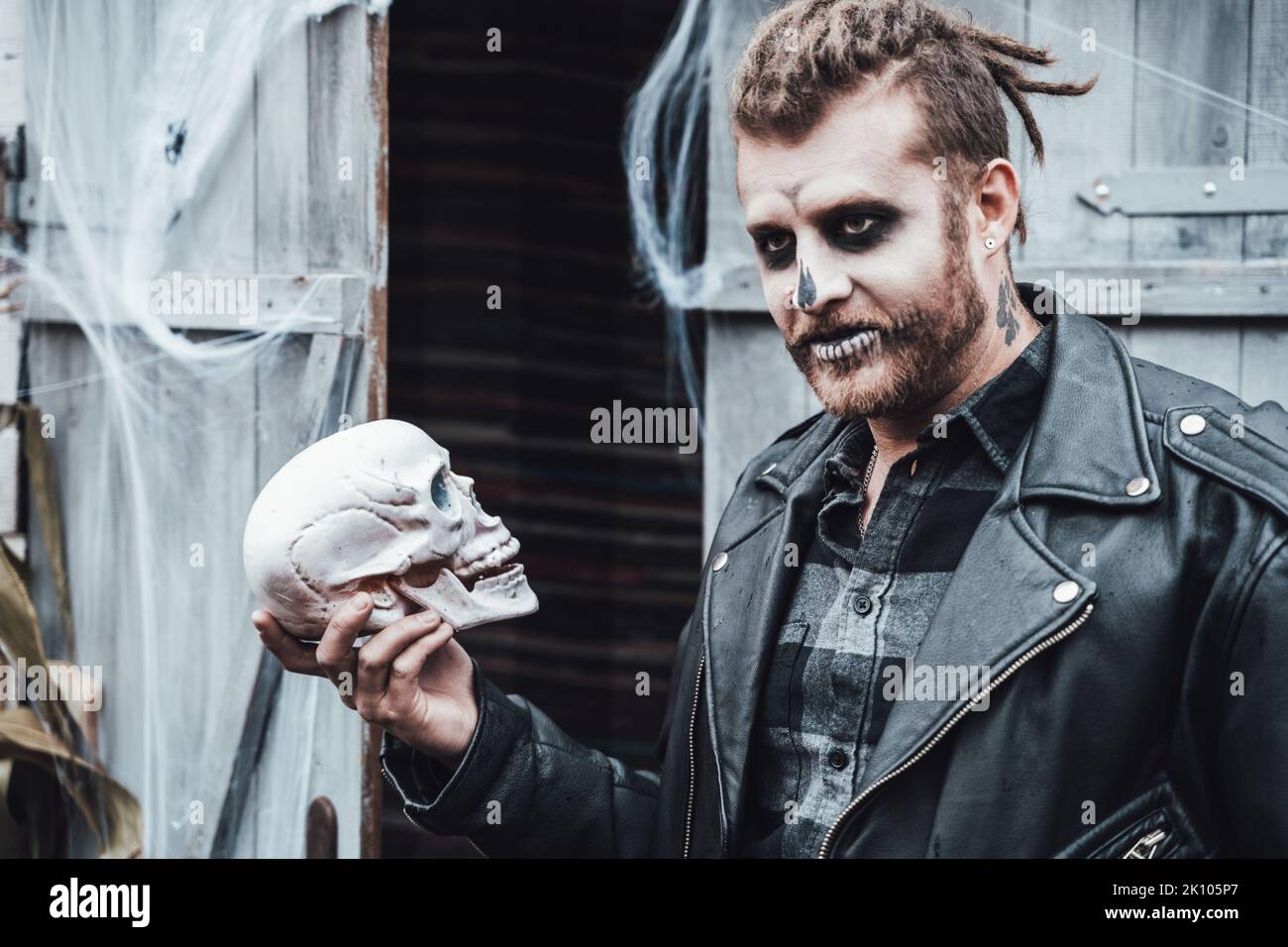 Scary man with dreadlocks looking at skull. Celebrating halloween ...